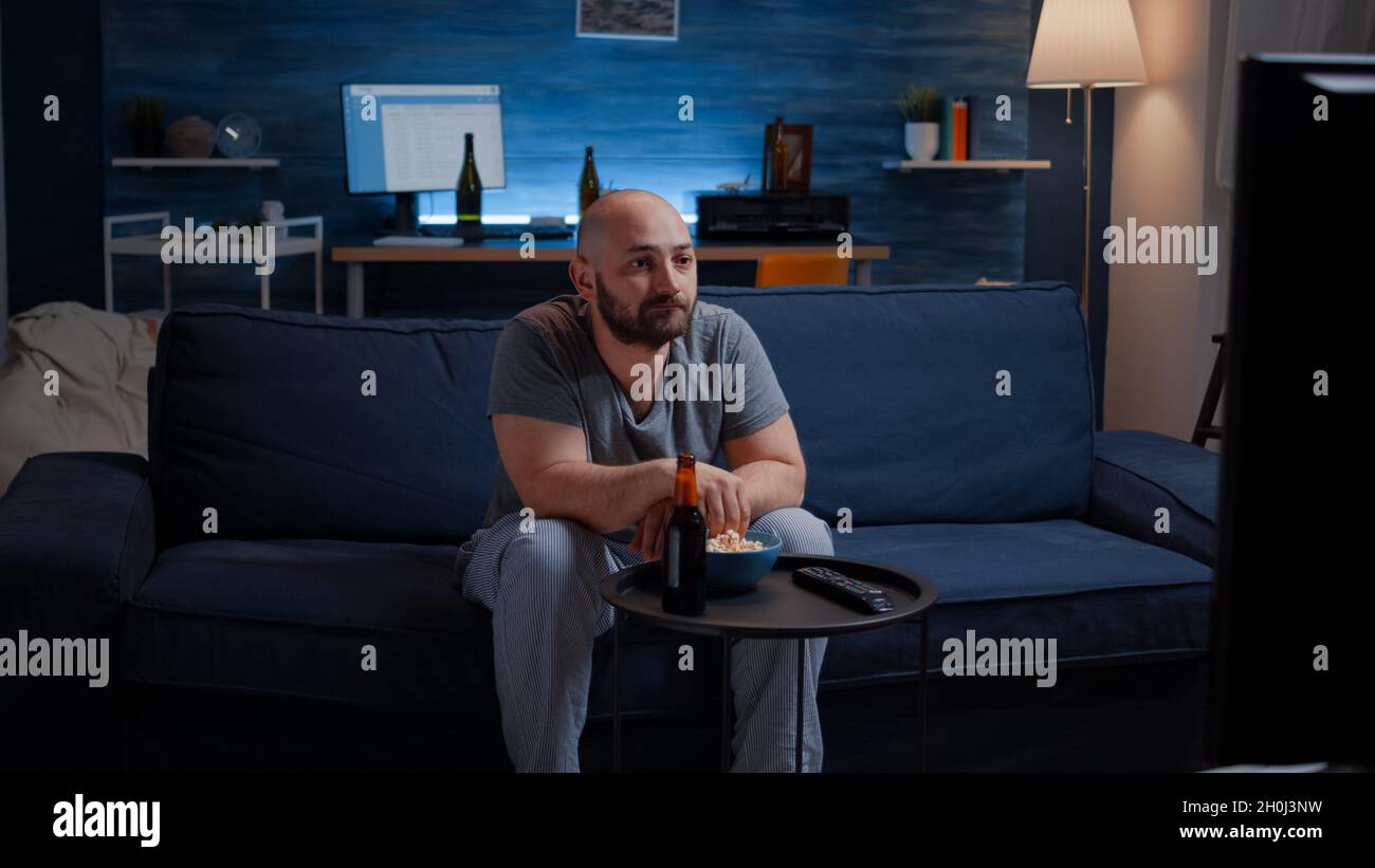 Scared shocked astonished man looking at horror movie at tv, eating ...