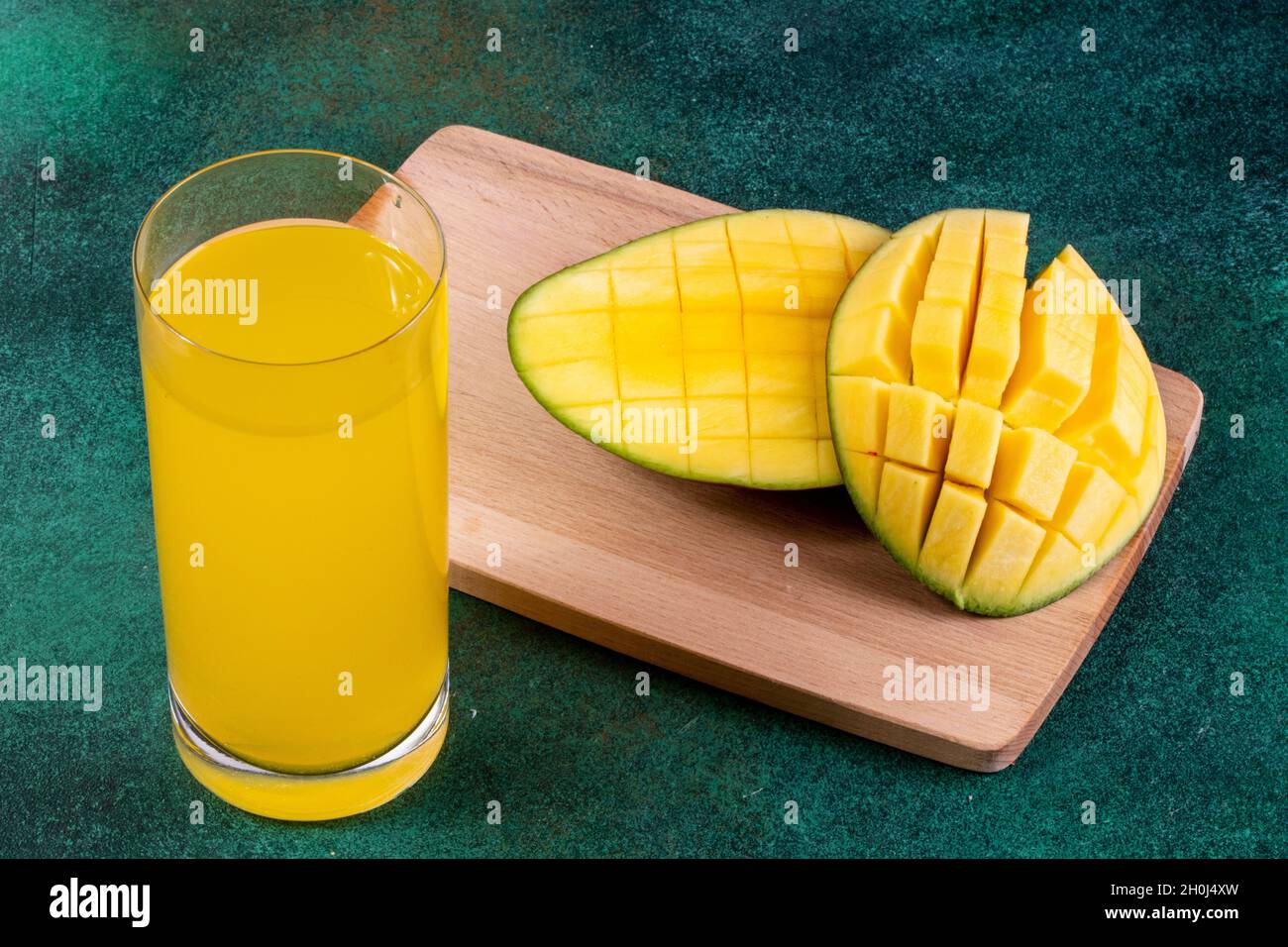 side view sliced mango on a blackboard with a glass of orange juice on ...