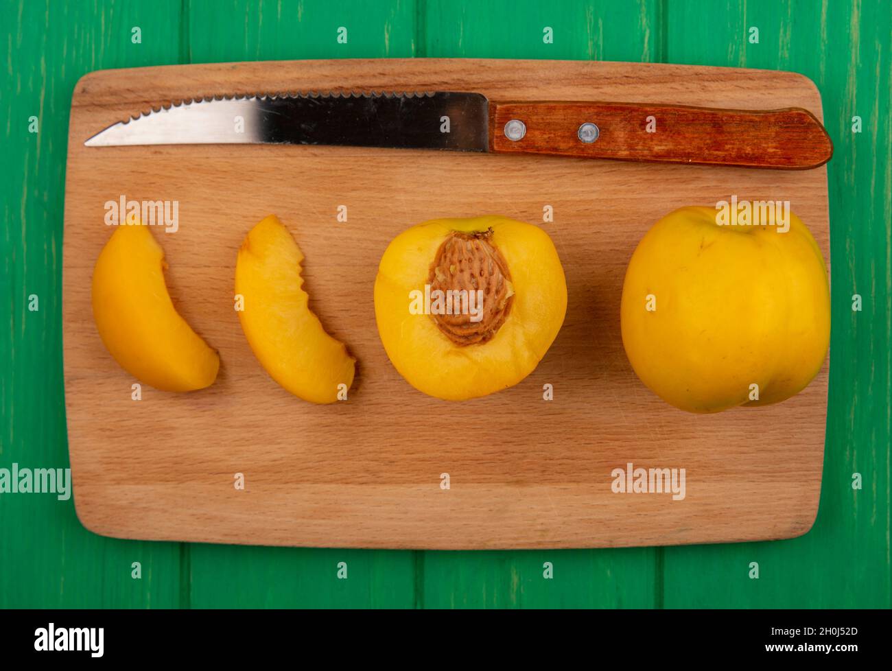 top view of whole cut and sliced apricots with knife on cutting board ...
