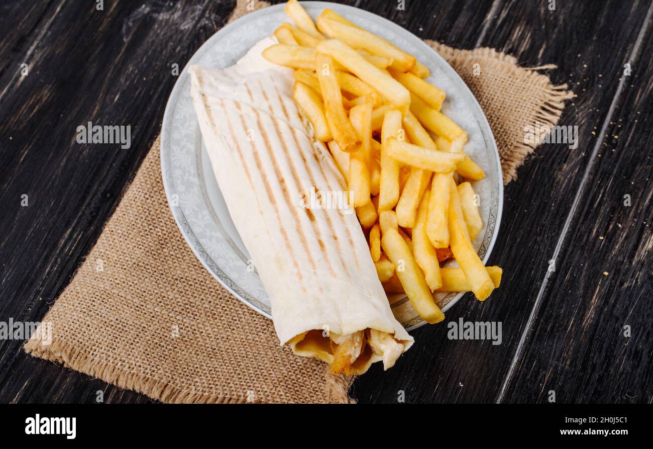 top view of chicken doner wrapped in lavash served with french fries on ...