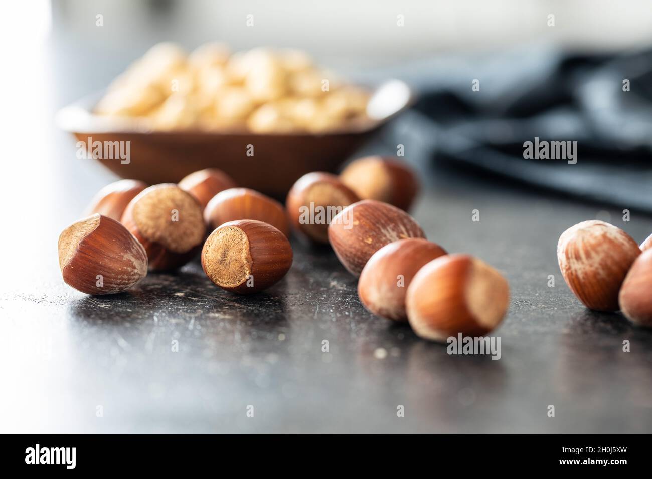 Unpeeled roasted hazelnut kernels on black table Stock Photo - Alamy