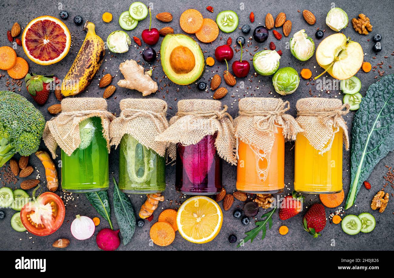 Colourful healthy smoothies and juices in bottles with fresh tropical ...