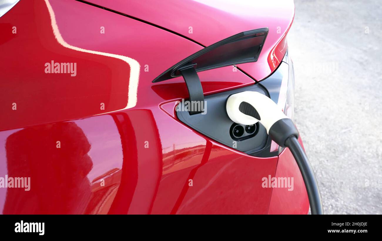 Close-up of a red electric car charging at an electric charging station ...