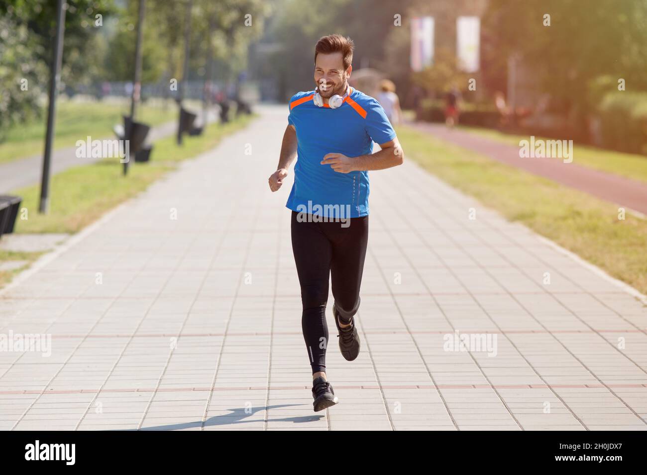 Satisfied handsome man running in park. Urban morning jogging Stock ...