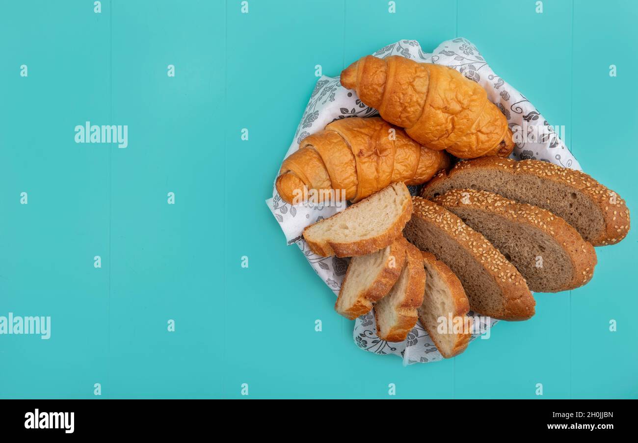 top view of breads as sliced seeded cob baguette and croissant in bowl ...
