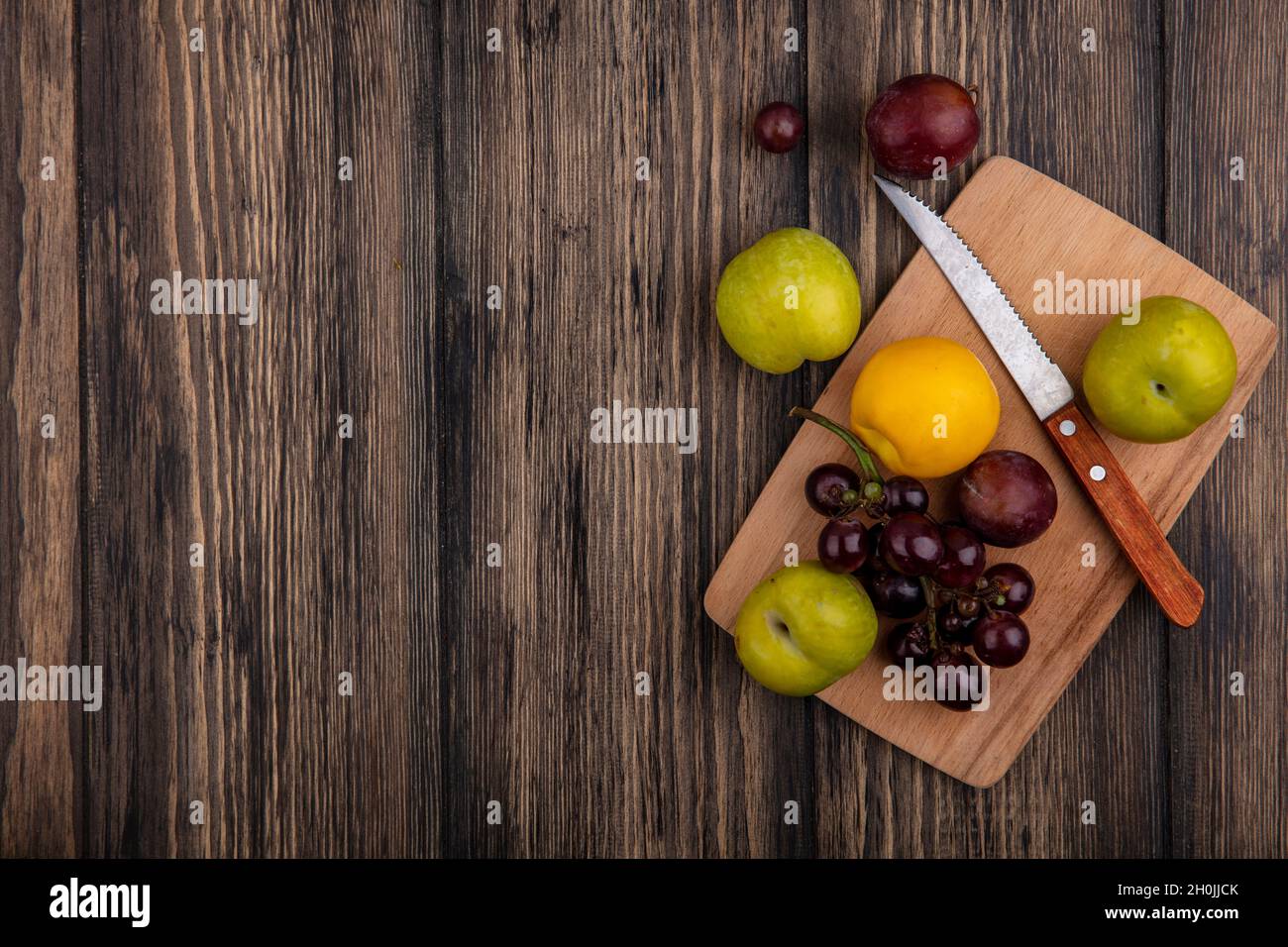 top view of fruits as grape nectacot pluots with knife on cutting board ...