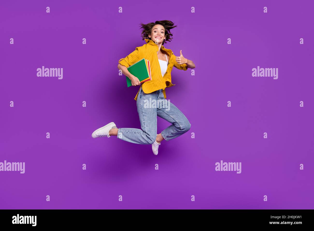 Photo of charming cute lady wear yellow shirt jumping high holding ...