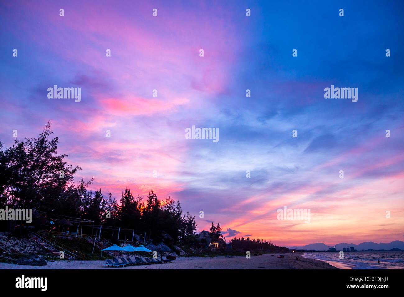 Pink light rays against a blue sky during a beach sunset on an bang ...