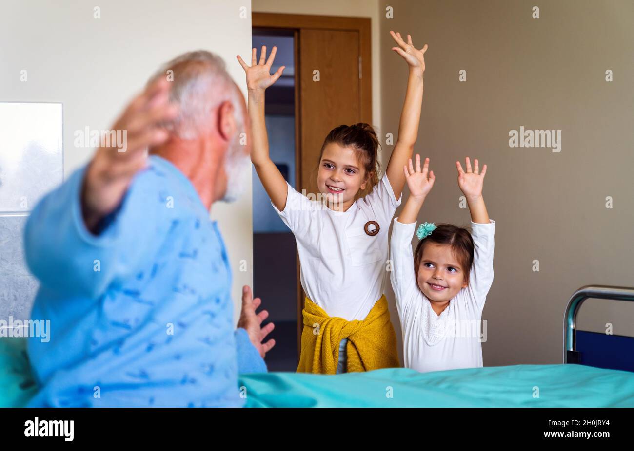 Happy grandchildren visiting grandfather at hospital ward. Support ...