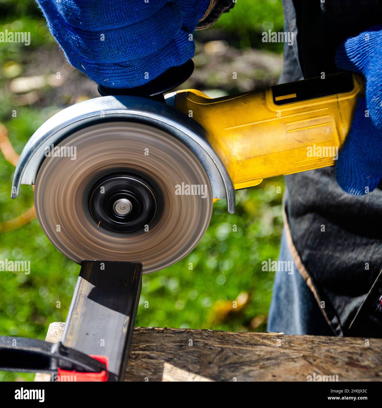 Heavy industry worker cutting steel with angle grinder at car service ...