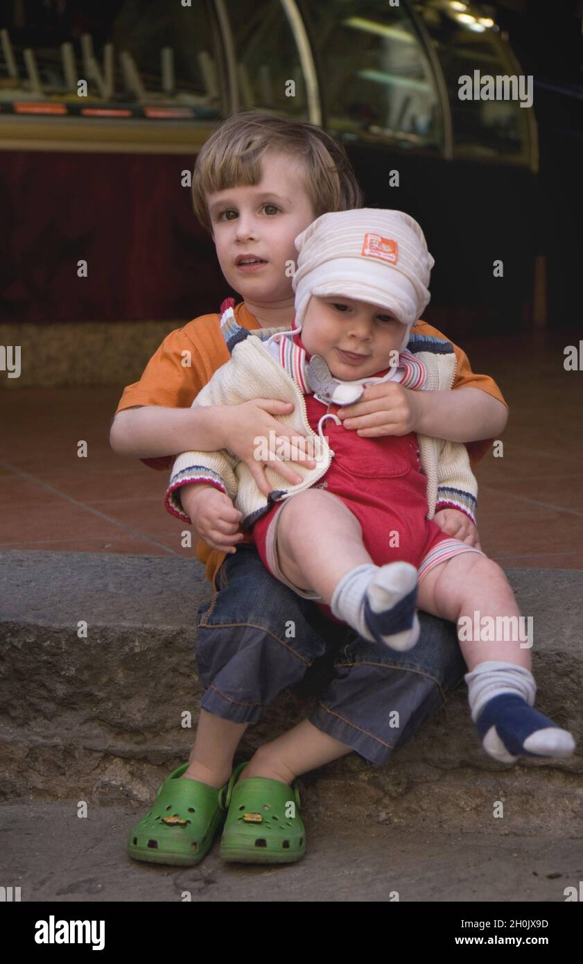 little boy sitting on a step with a baby on his lap Stock Photo - Alamy
