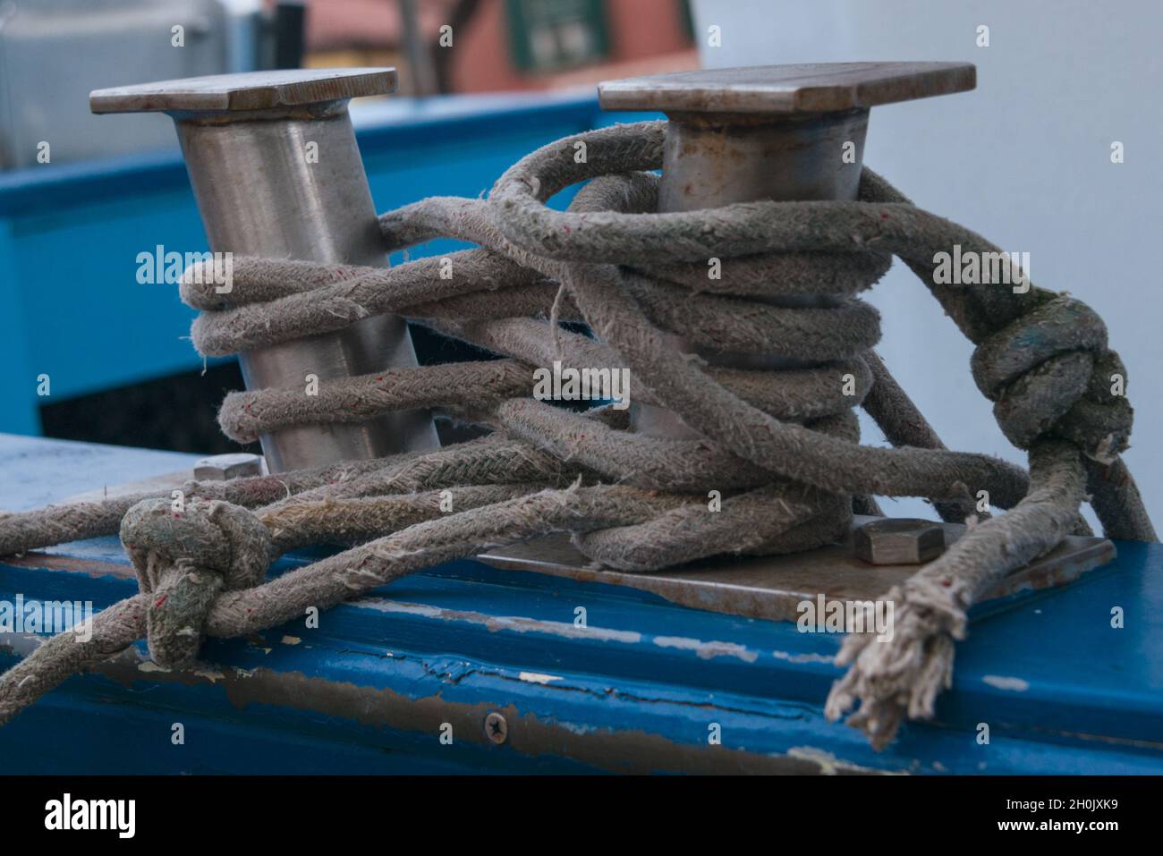 Ship bollard with grey ropes to which a blue boat is moored Stock Photo ...