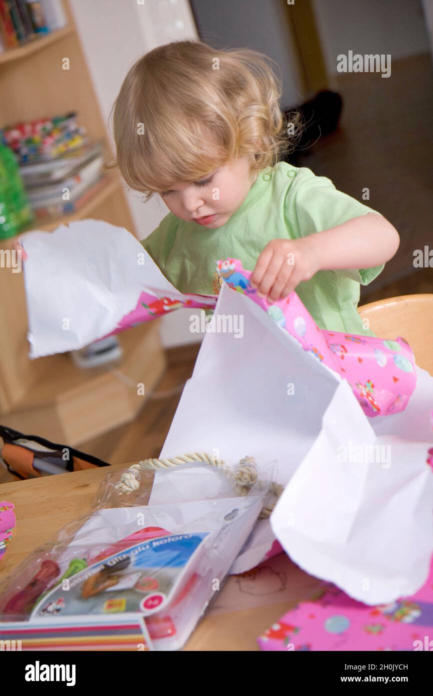 children's birthday party, little girl unwrapping her birthday presents ...