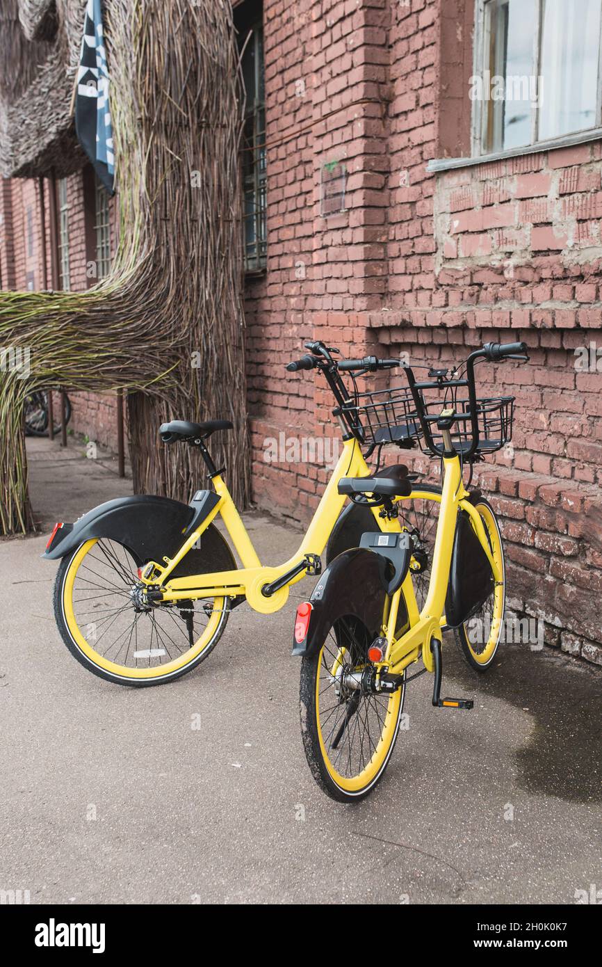Yellow urban bicycles with baskets in the public domain near the red ...