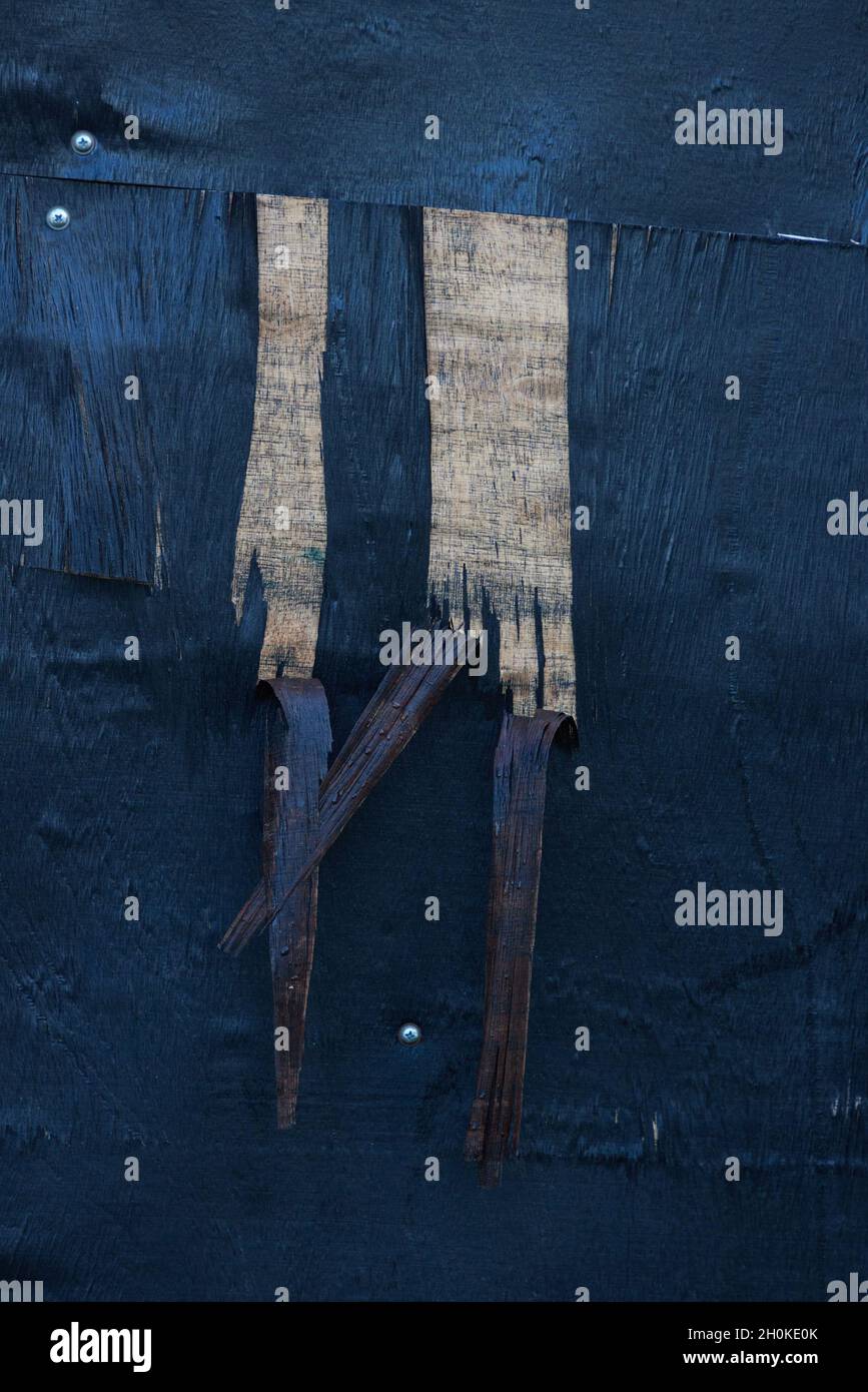 Thin layer of wood seen peeling of black painted plywood creating an ...