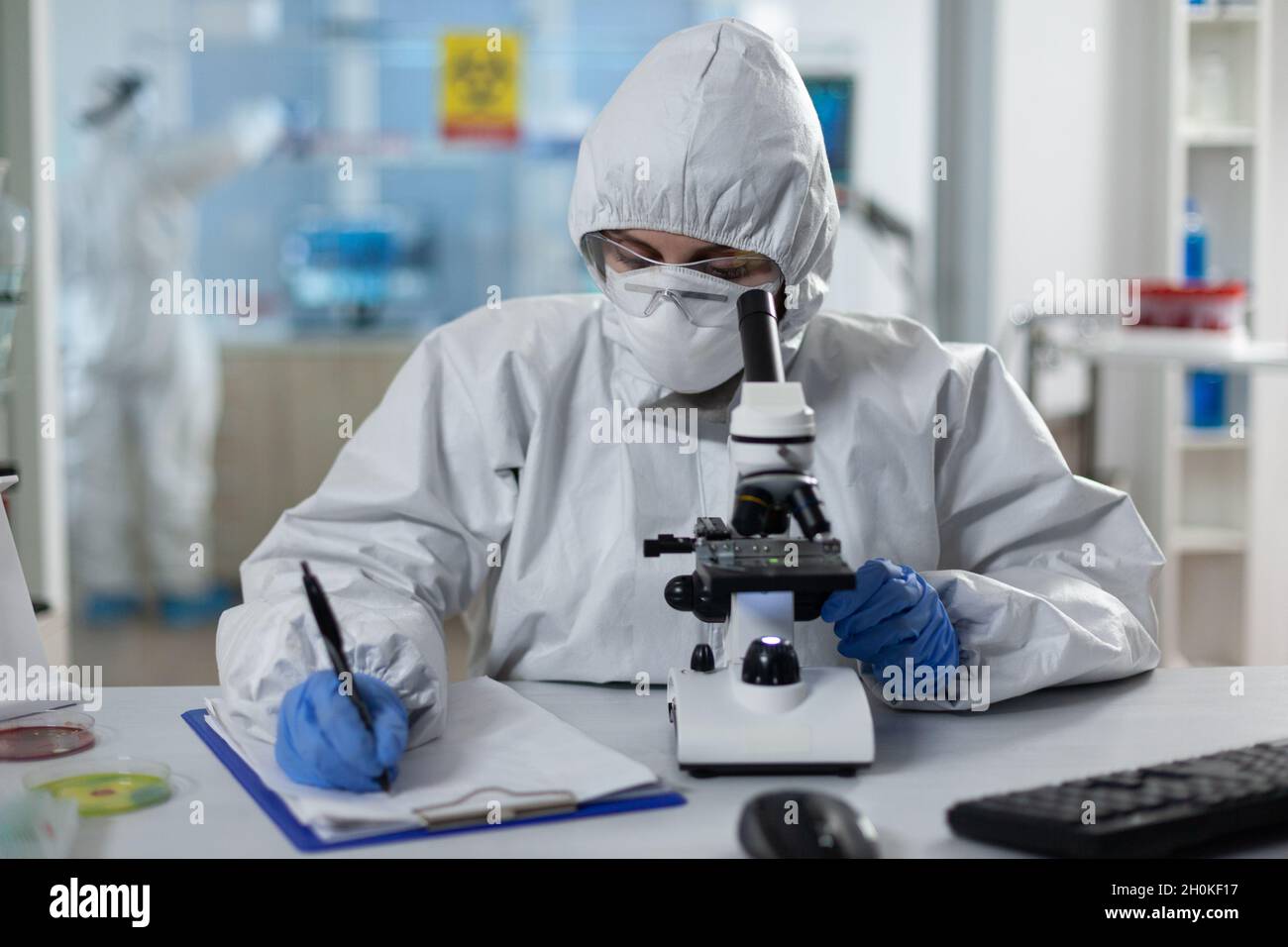 Biologist researcher wearing protective suit analyzing chemicals using ...