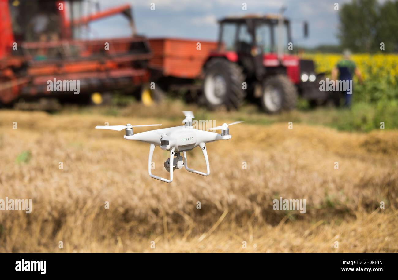 Drone flying in front of tractor and combine harvester in field in ...