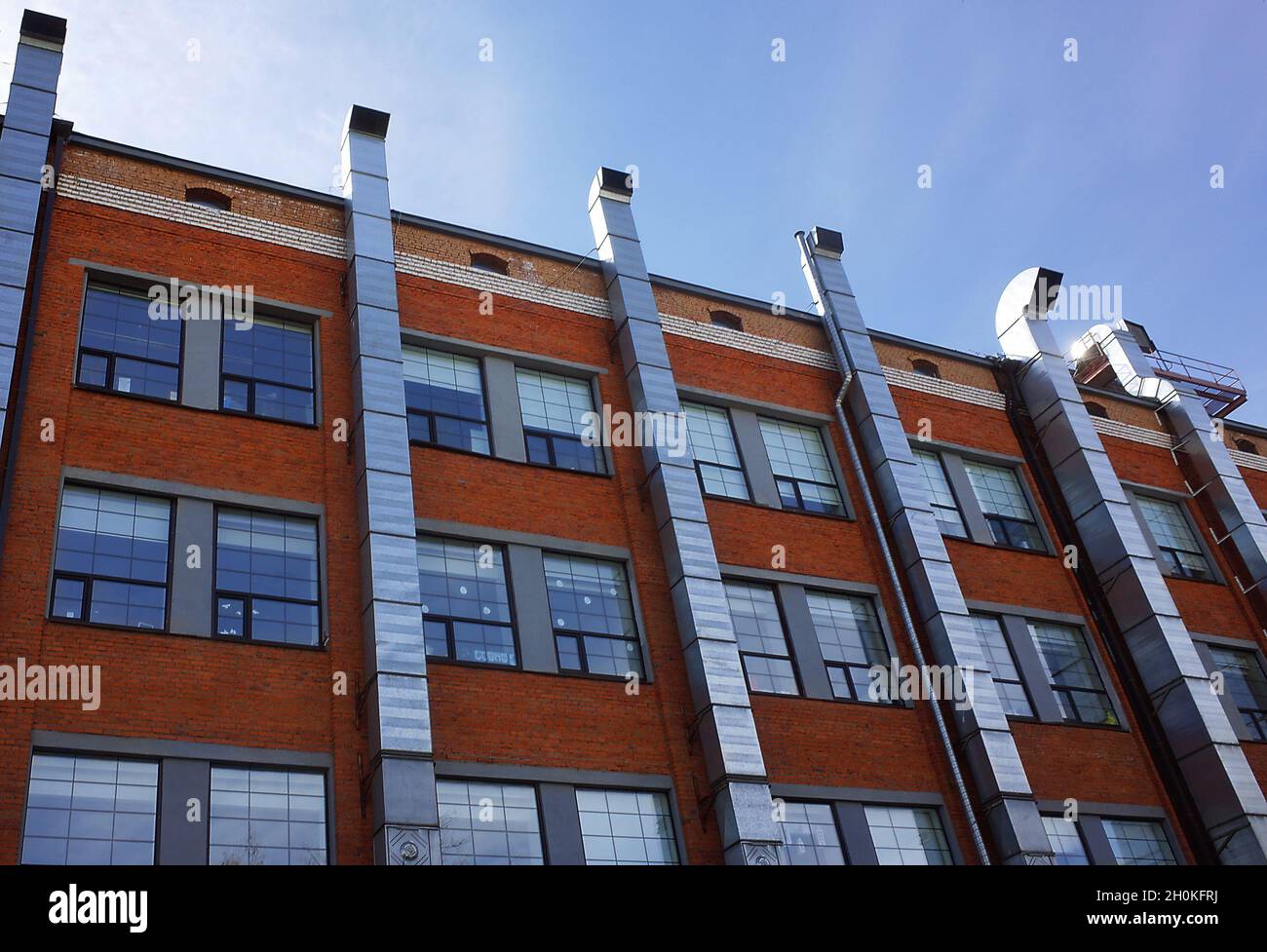 Shiny square pipes of the ventilation system on the facade of a brick ...