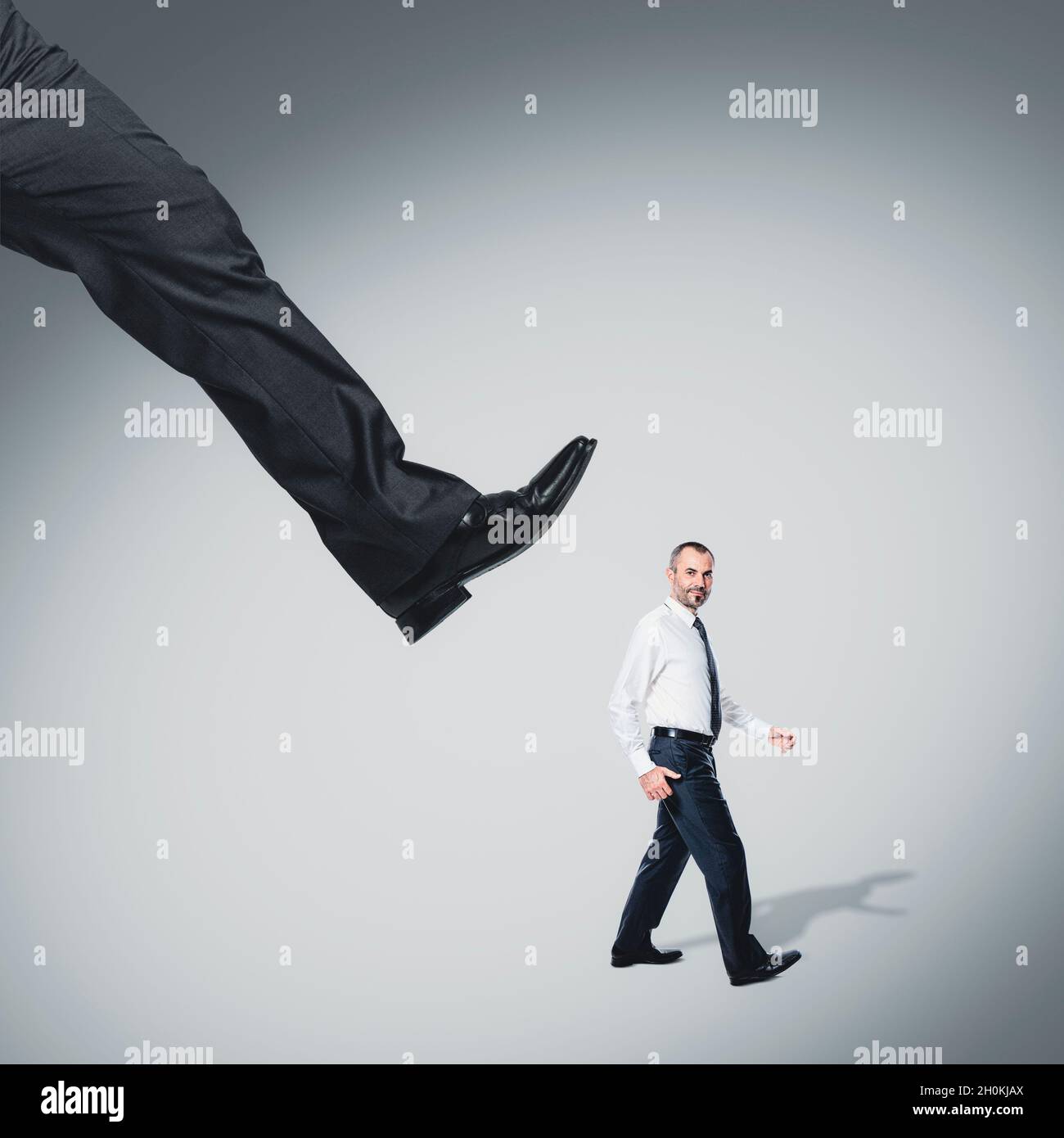 businessman walking calmly and a big foot hangs over him Stock Photo ...