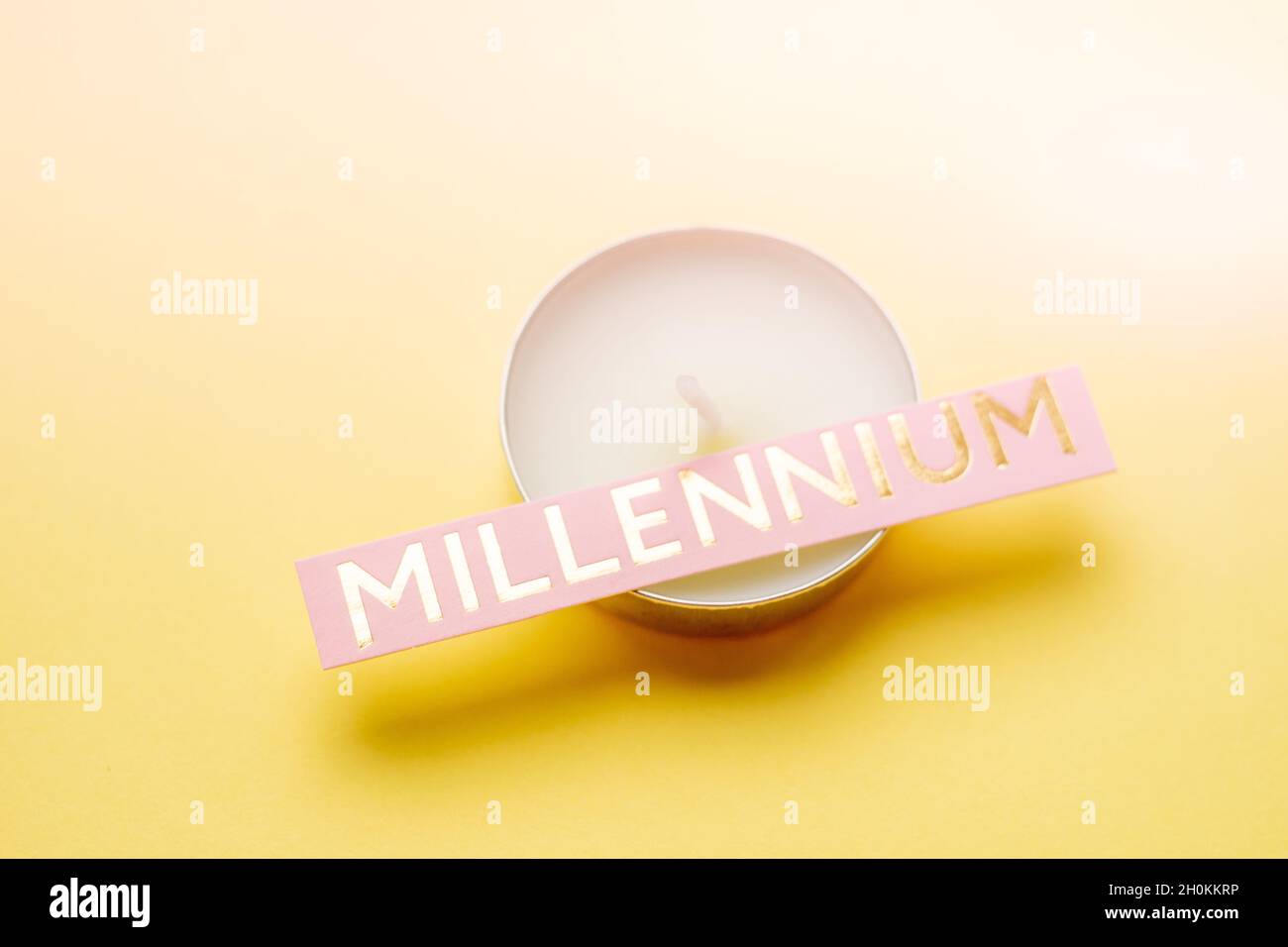 Paper cut with millennium text and one new white candle on yellow table ...