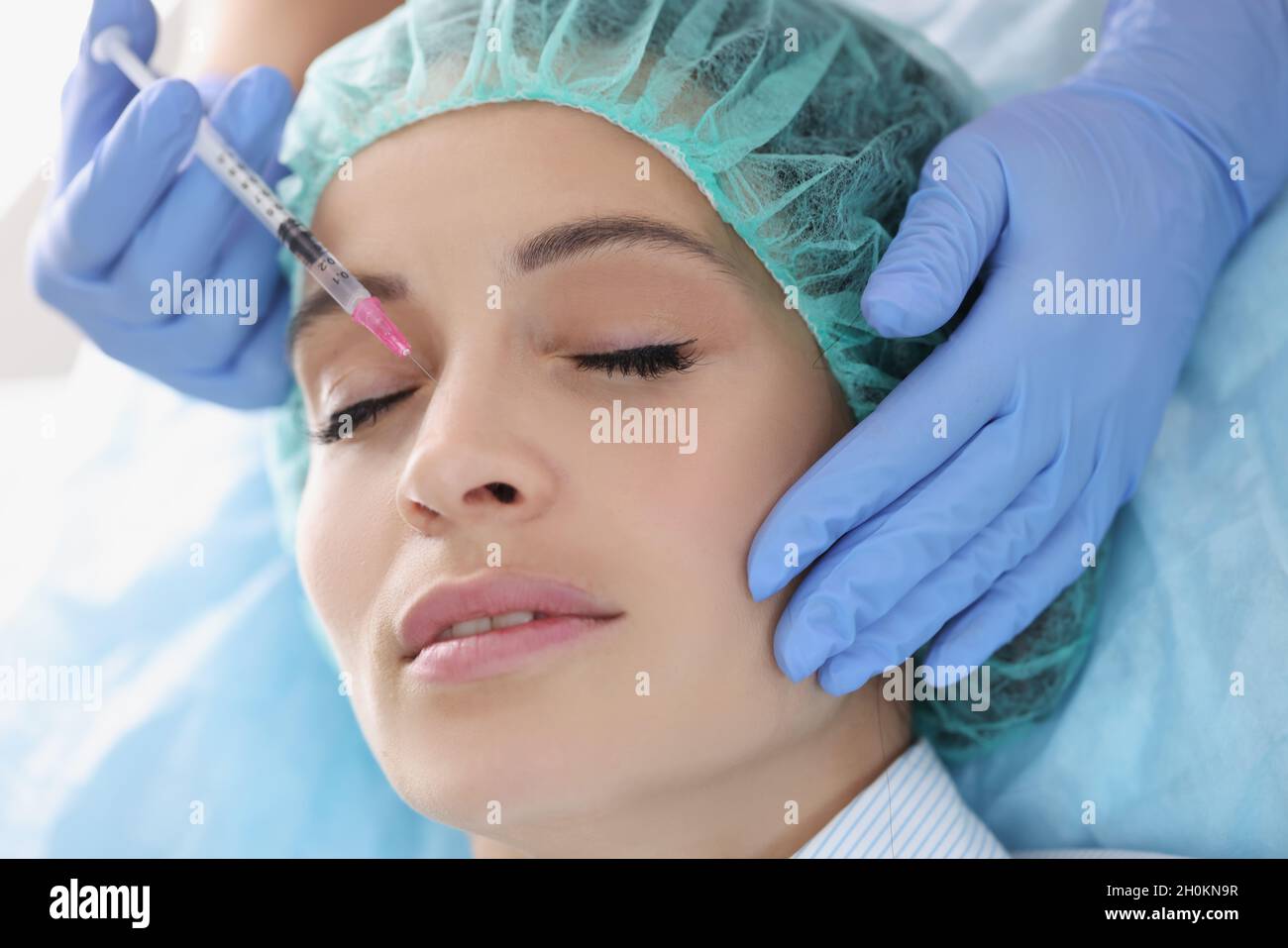 Doctor cosmetologist making injection in nasal area of woman patient in ...