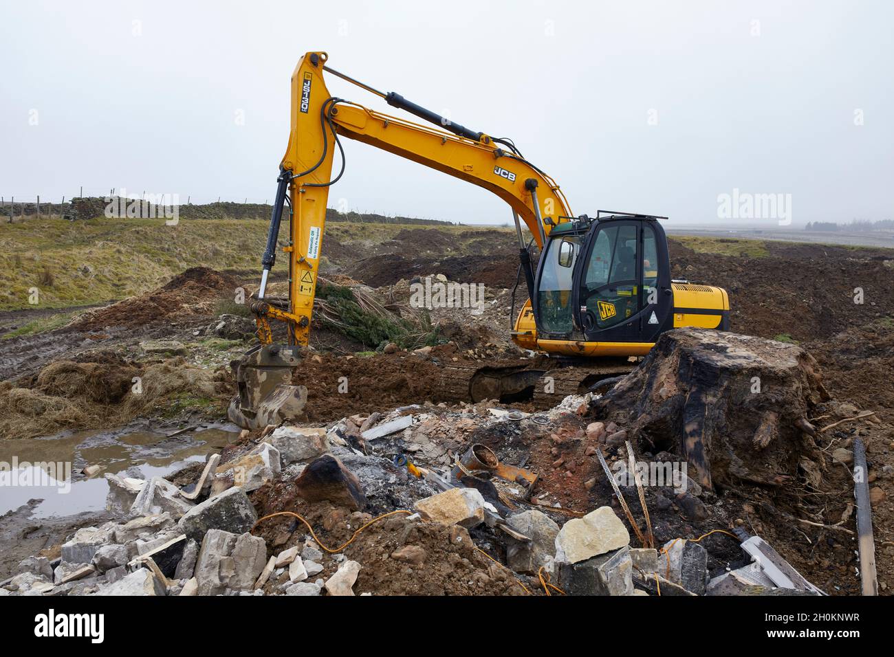 At rest, a JCB digger begins to clear a disused quarry and tip Stock ...