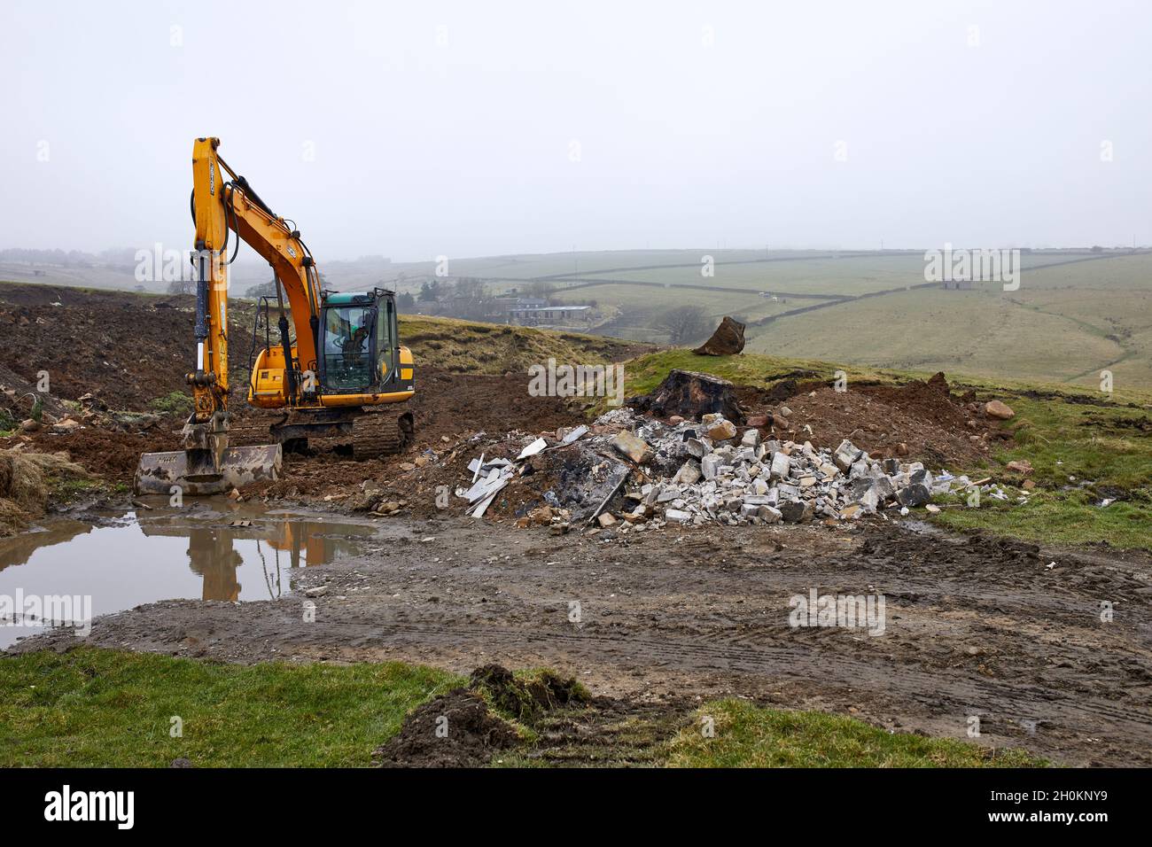 At rest, a JCB digger begins to clear a disused quarry/tip Stock Photo ...