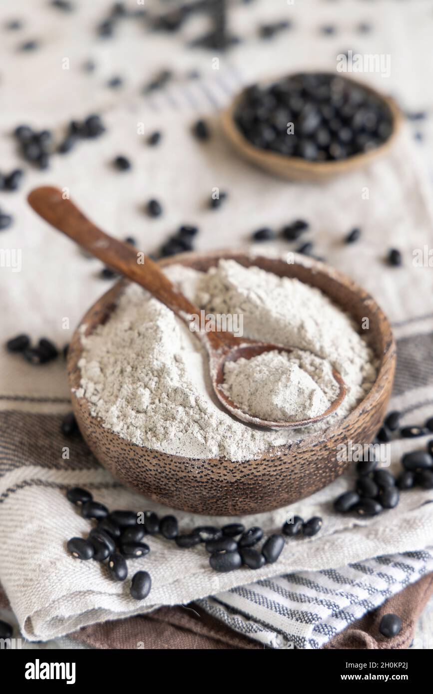 Wooden bowl with black beans flour and dried beans with a wooden spoon ...