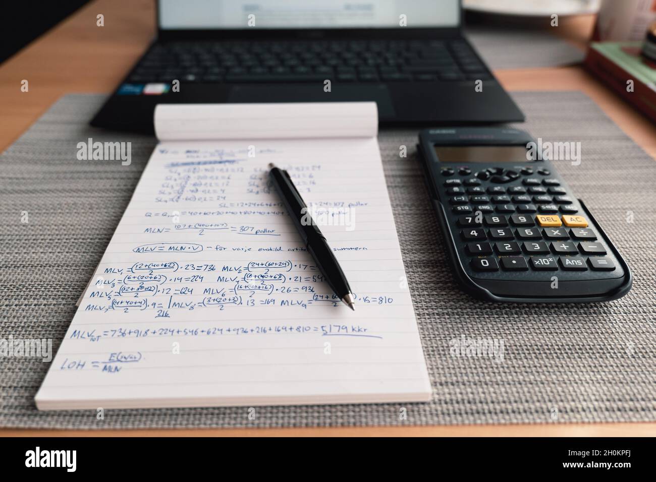 Studying for exams with notebook, pen, calculator and laptop computer ...