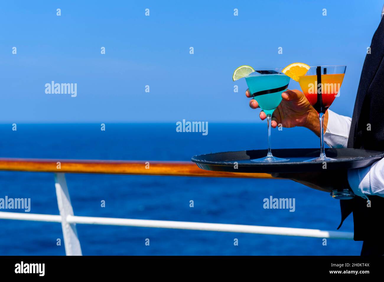 Tray of cocktails served by a bartender on the deck of a ship with the ...