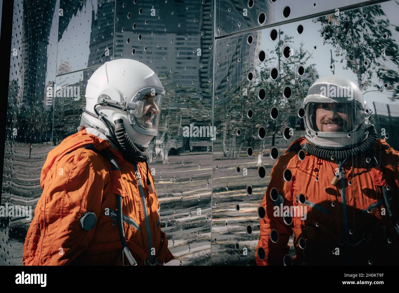 Portrait of smiling astronaut wearing orange spacesuit and space helmet ...