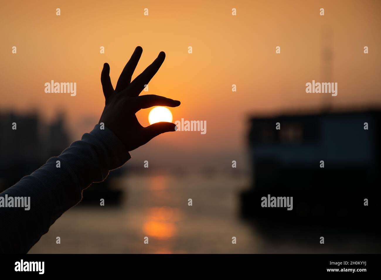 female Hand or fingers hold the warm rays of sunshine or sun during ...