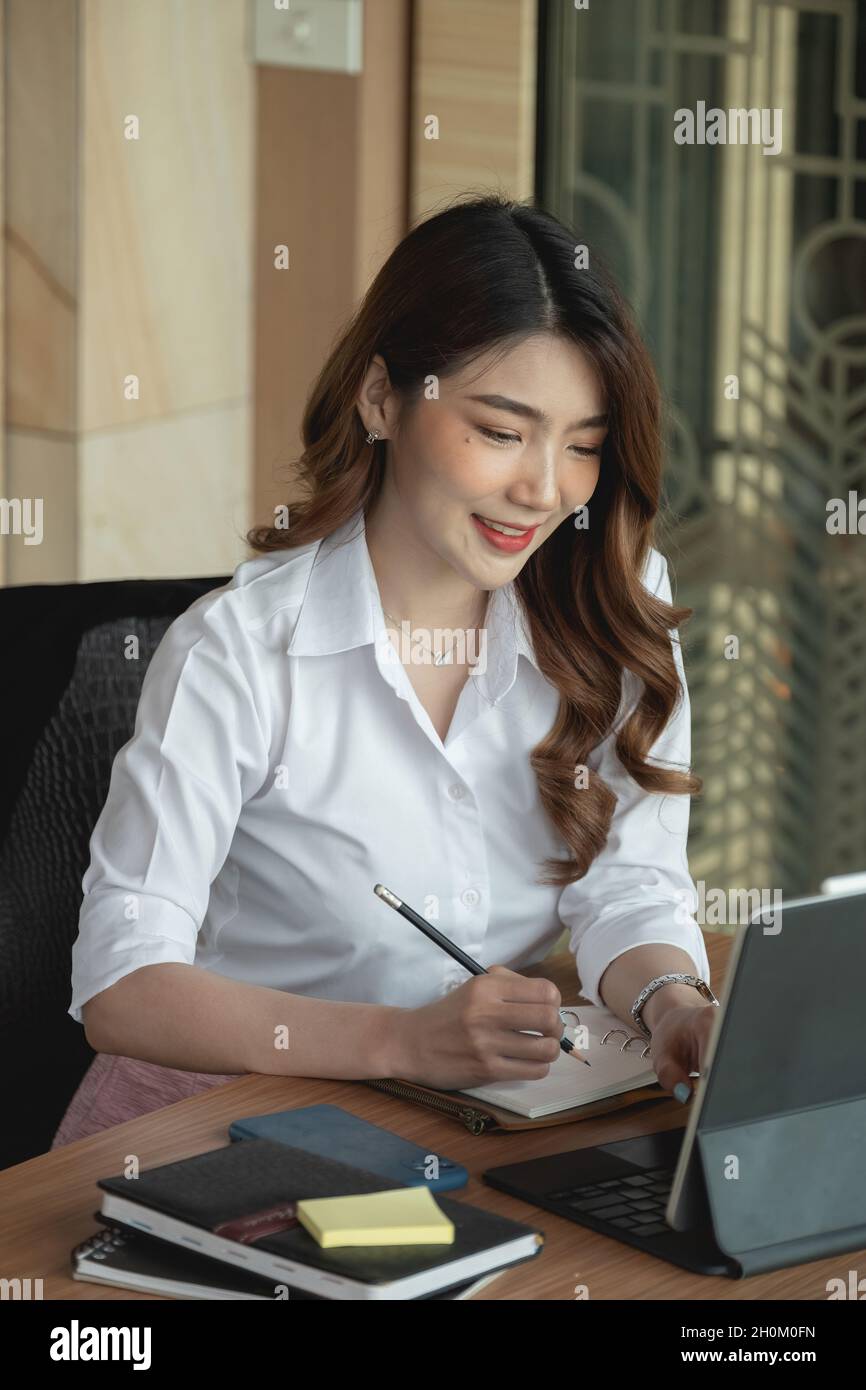 Portrait charming asian woman taking note on notepad while video ...