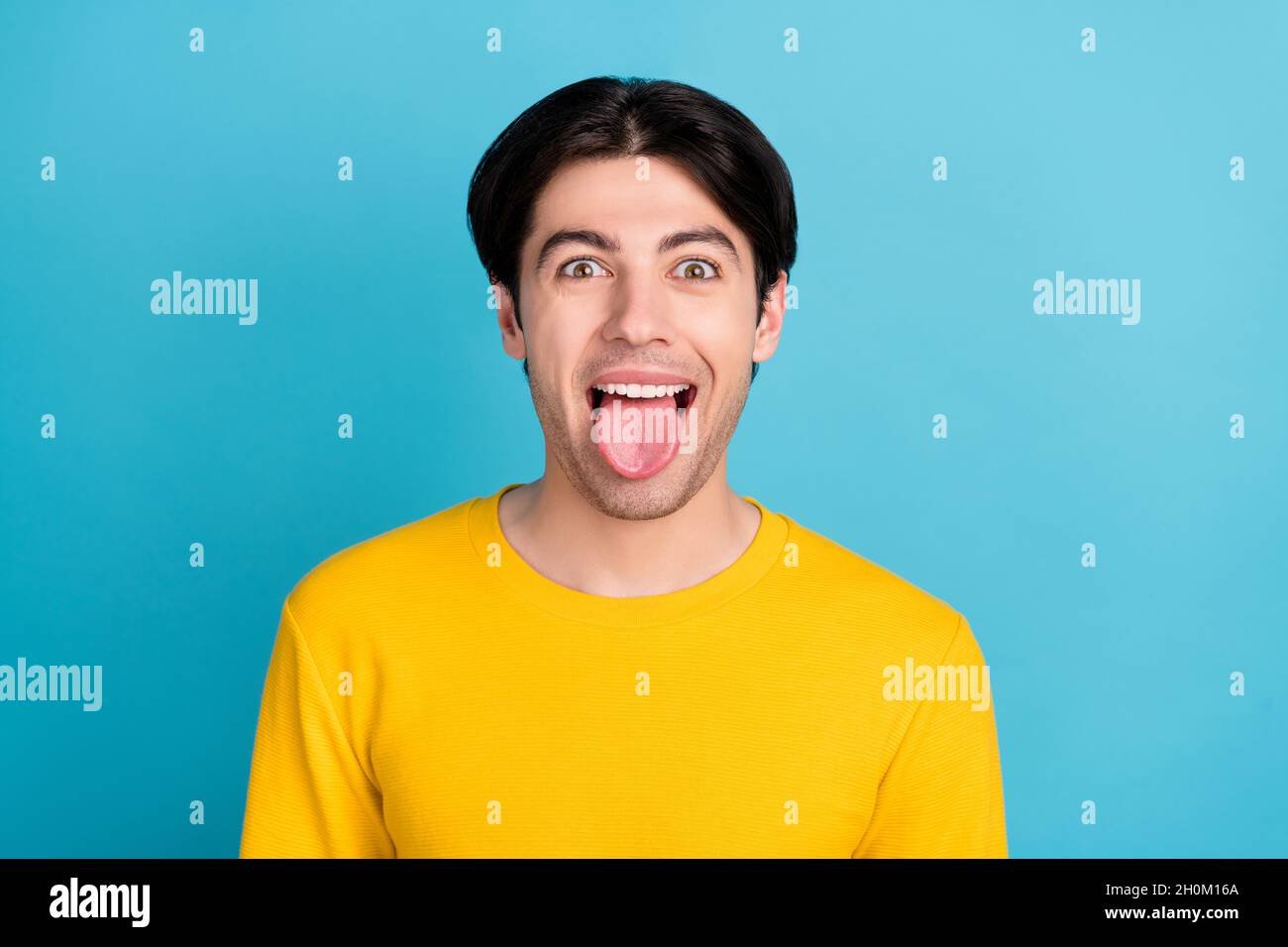 Photo of millennial funny guy tongue out wear yellow shirt isolated on ...