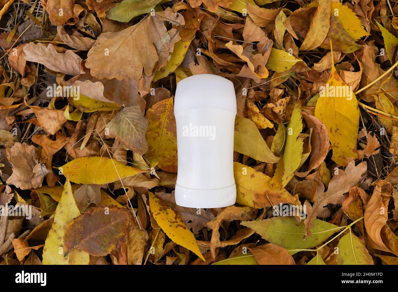 Mock up a bottle of deodorant on yellow autumn maple leaves background ...