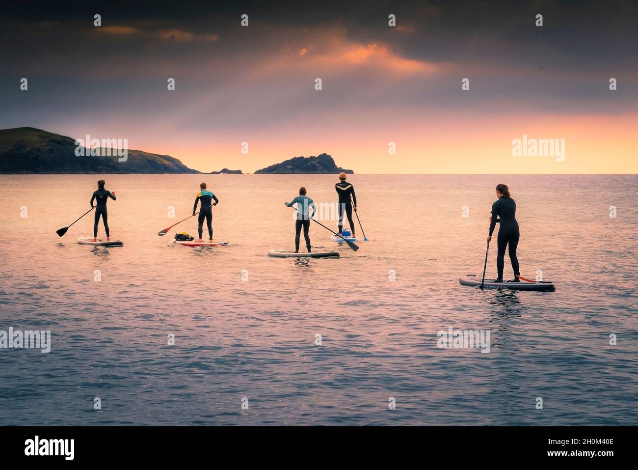 A group of Stand Up Paddleboarders paddling across Fistral Bay in ...