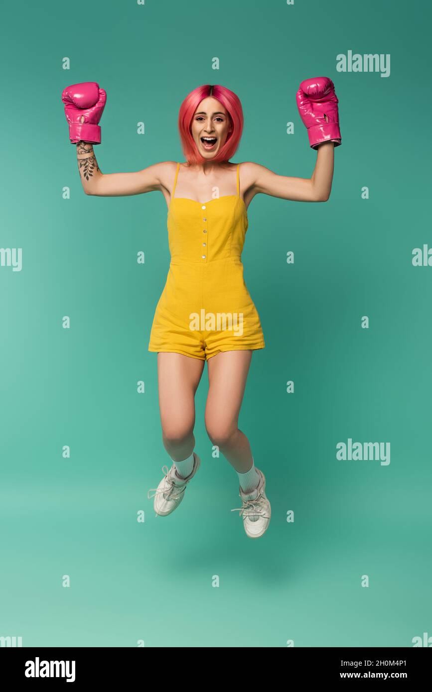 full length of amazed young woman with pink dyed hair in boxing gloves ...