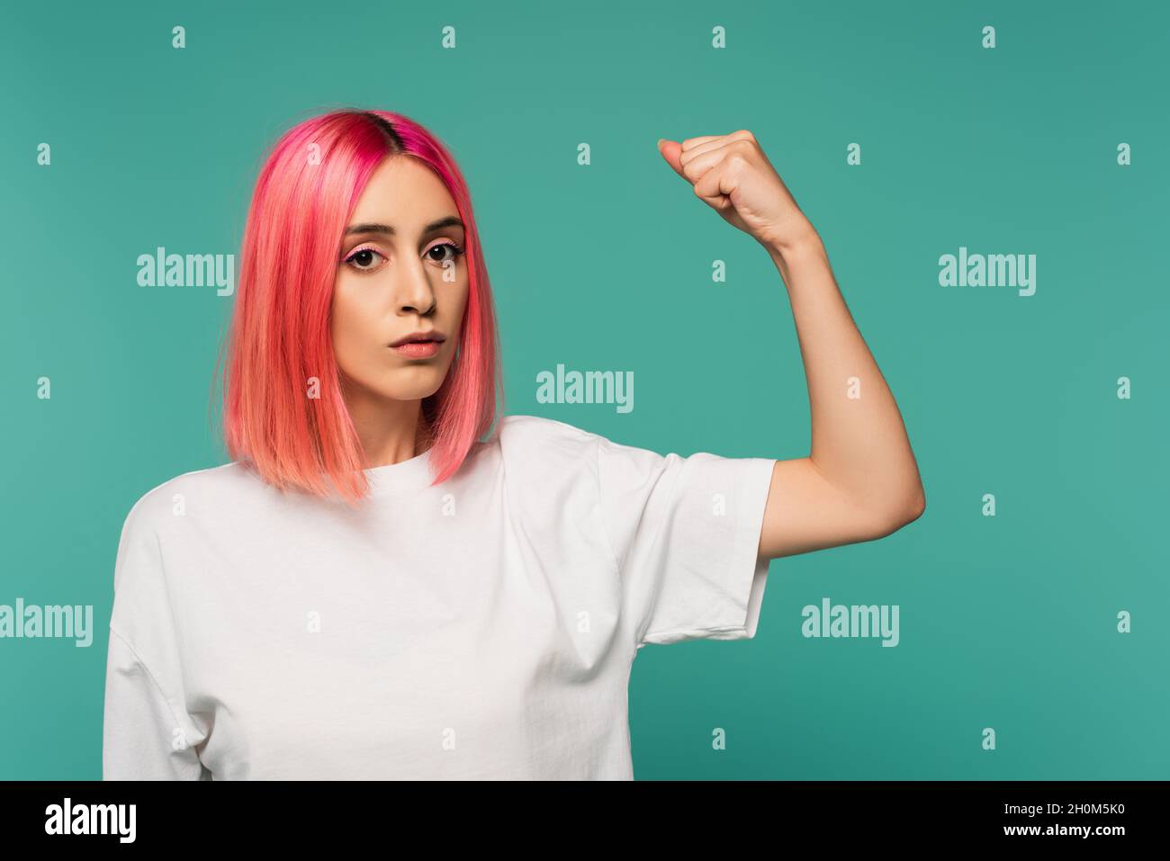 strong young woman with pink dyed hair showing muscle isolated on blue ...