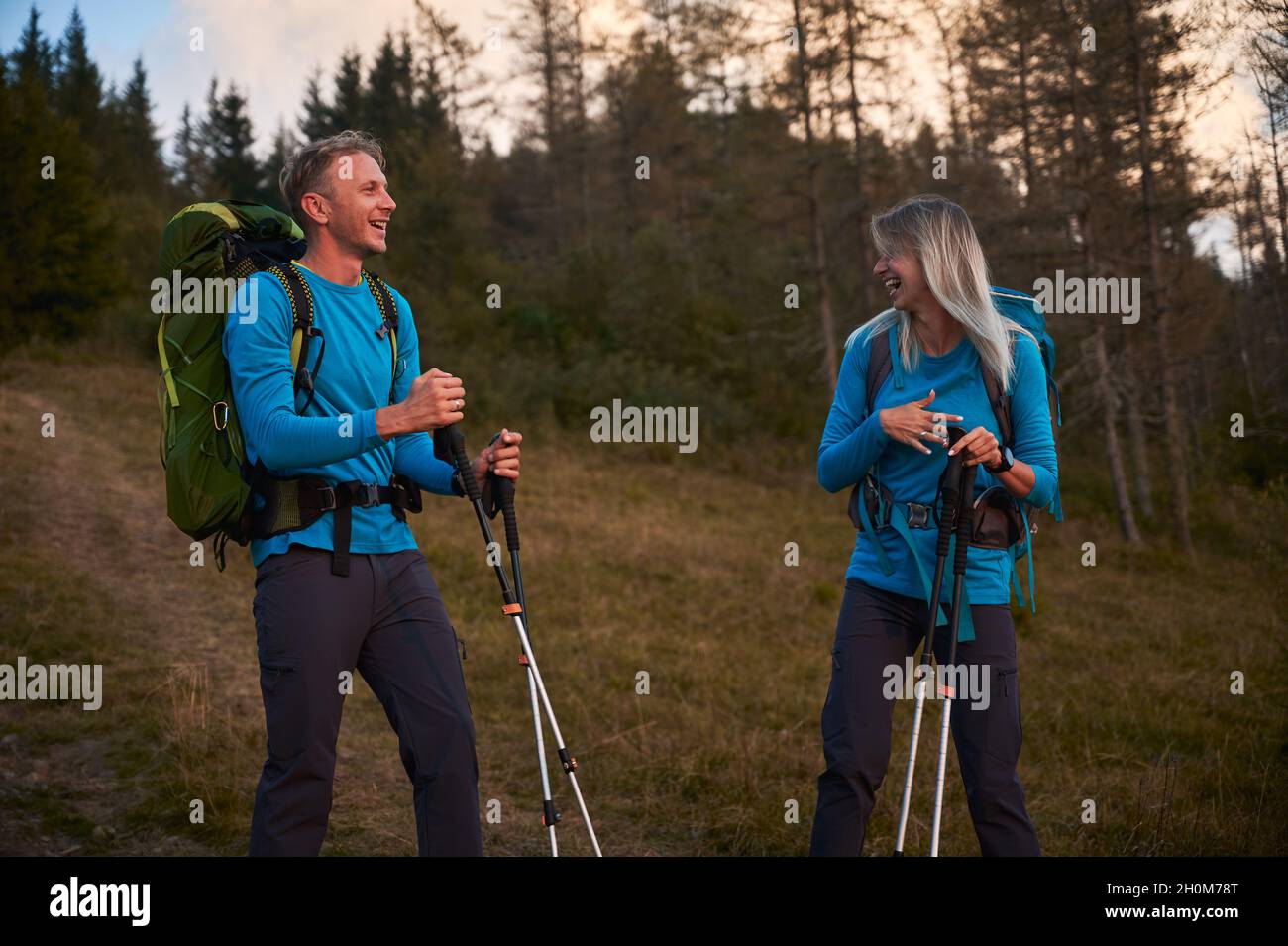 Couple of hikers laughing together while walking outdoors on forest ...