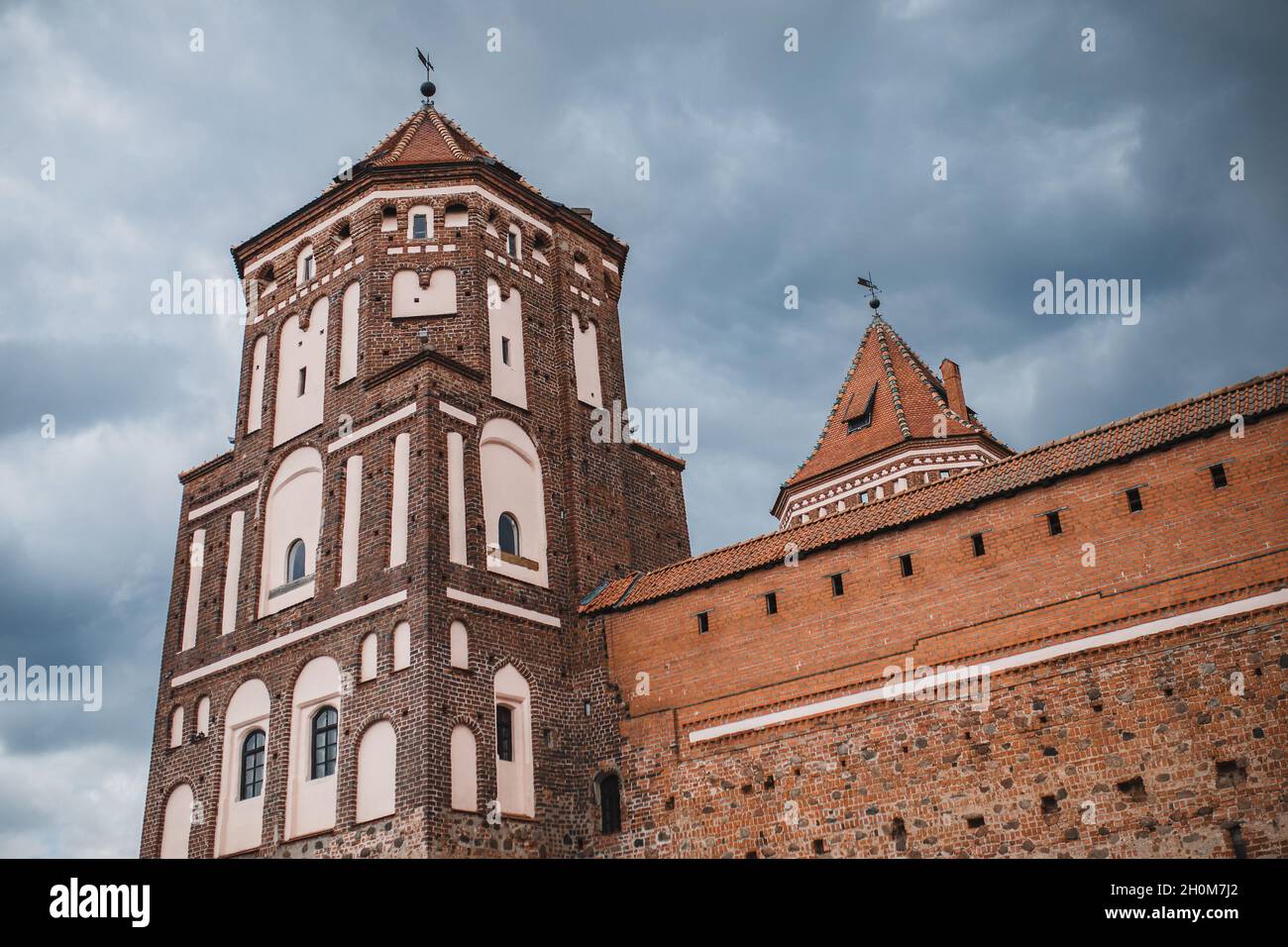 Square tower and massive impregnable walls of an old medieval red brick ...