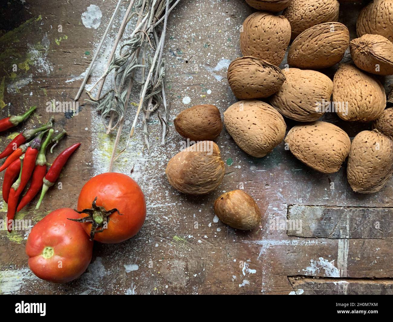 Top view of a pile of scattered almonds next to spicy red peppers and ...
