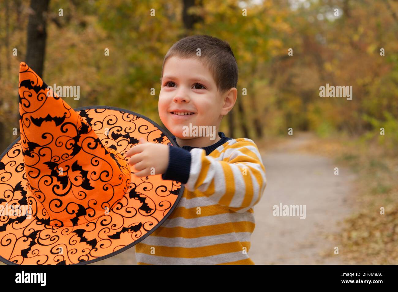 A boy in a striped jacket holds a large orange hat with bats Stock ...