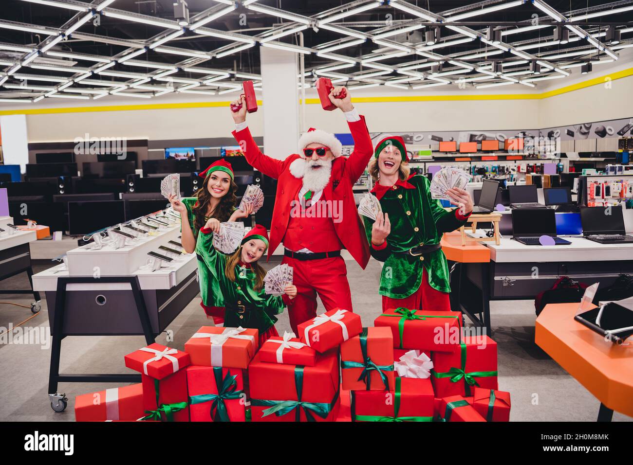 Photo of good mood funky santa claus assistants wear costumes smiling shooting gun holding cash ...