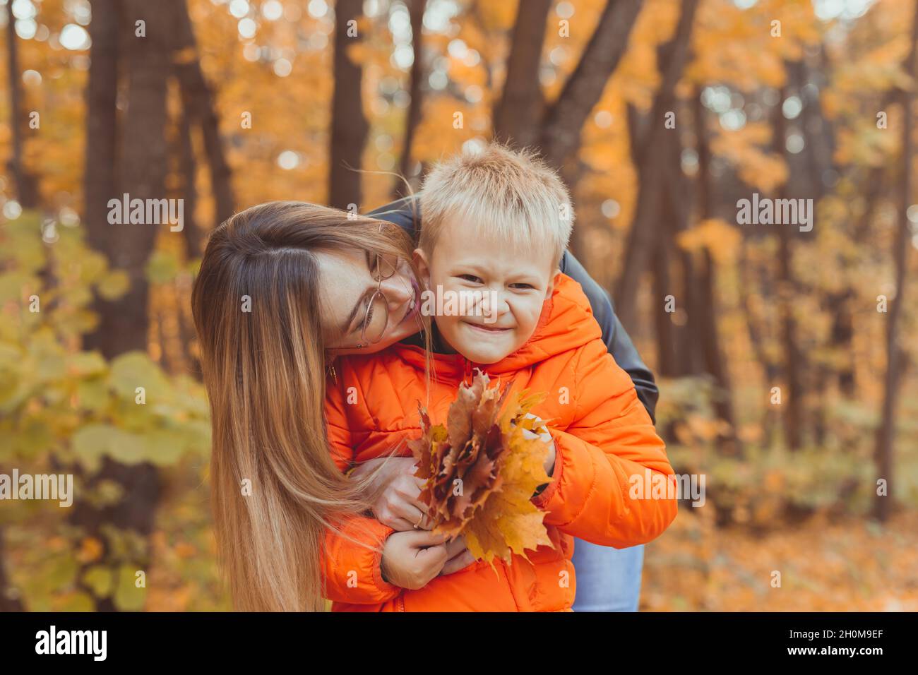 Mother hugging her child during walk in autumn park. Fall season and ...