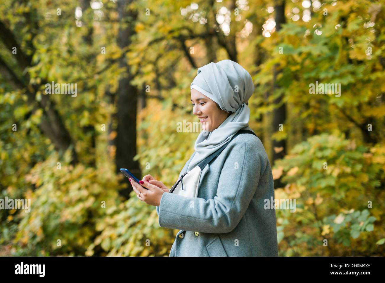 Pretty muslim woman using mobile phone outdoor. Arabic female wearing ...