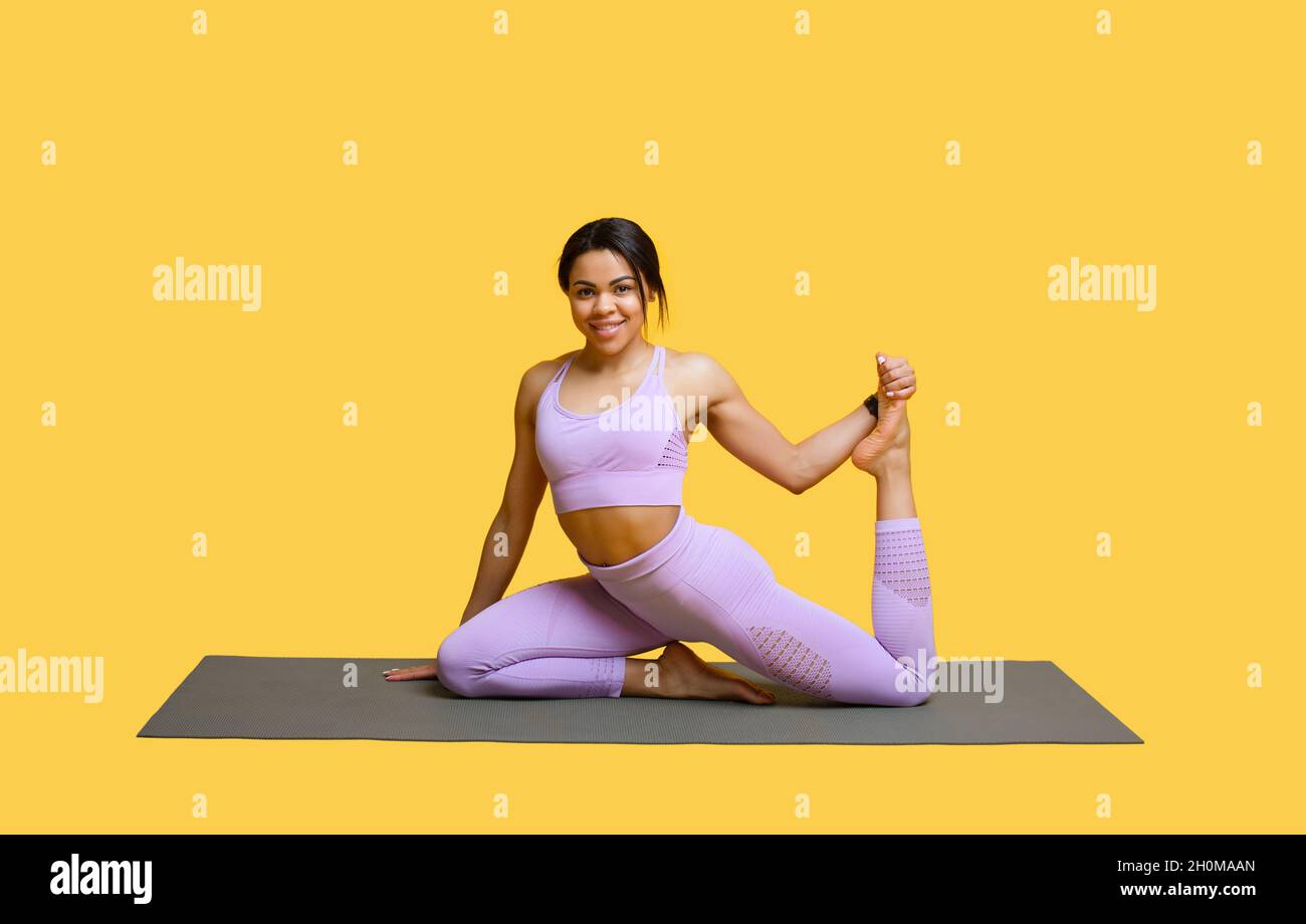 One legged king pigeon pose. African american lady stretching leg and ...