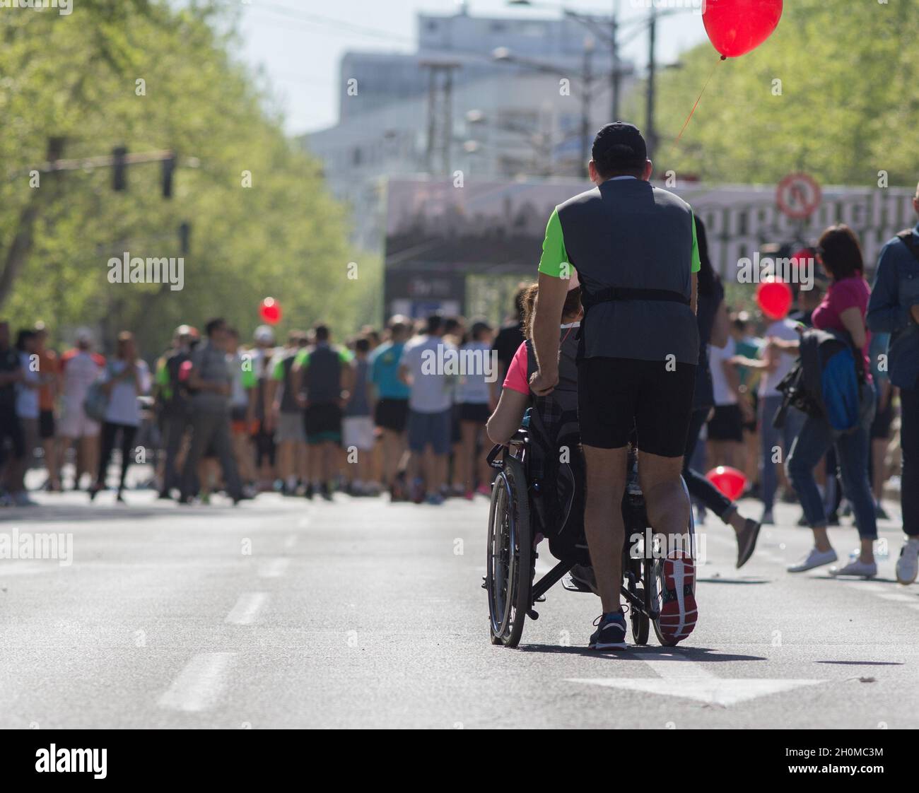 Man pushing wheelchair with disabled girl at street marathon Stock ...
