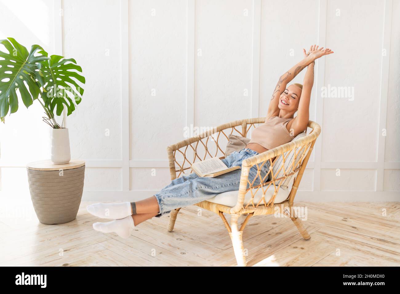 Gorgeous lady stretching in wicker armchair while reading book ...