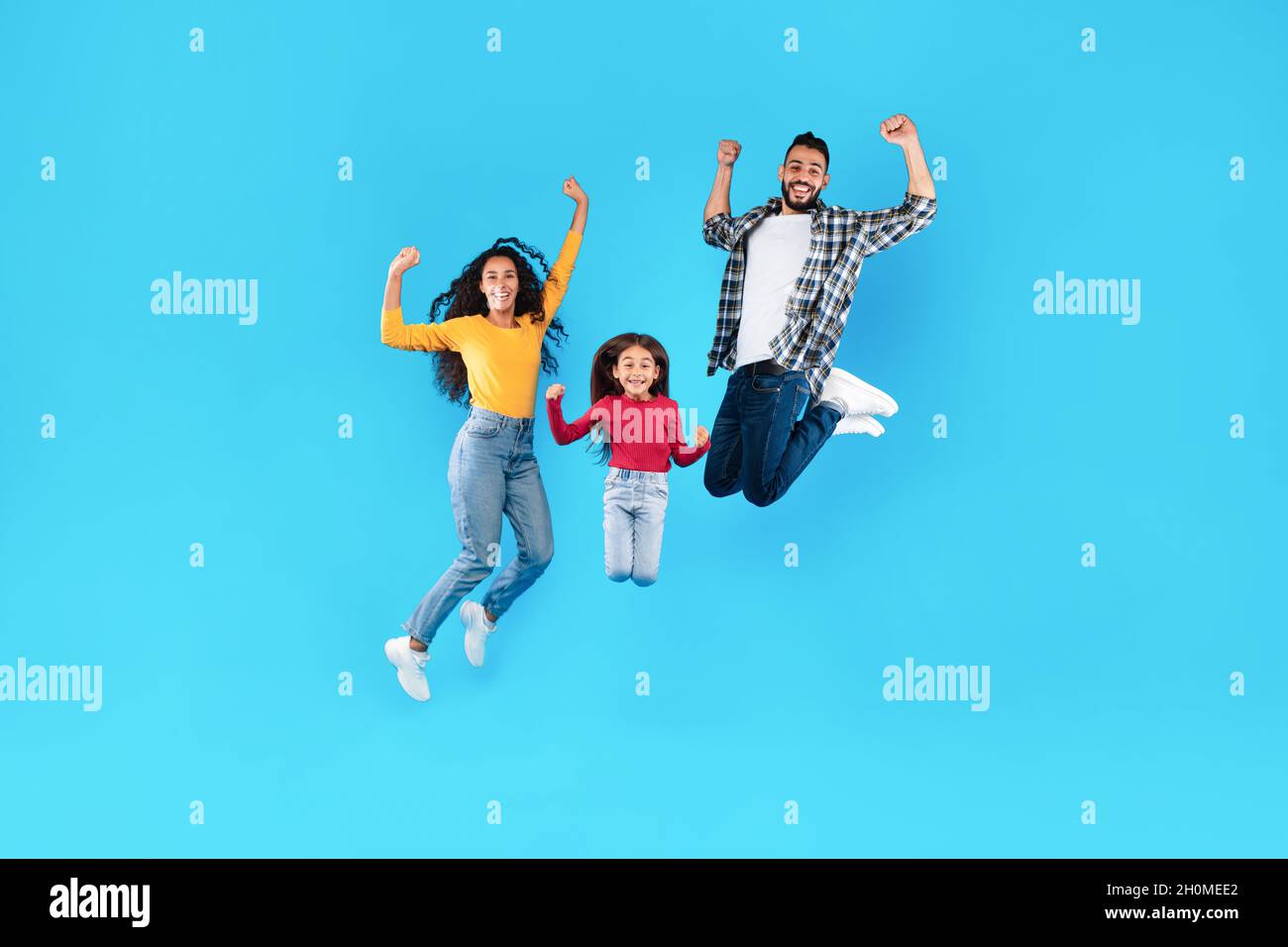 Joyful Arabic Family Jumping Shaking Fists Over Blue Background Stock ...