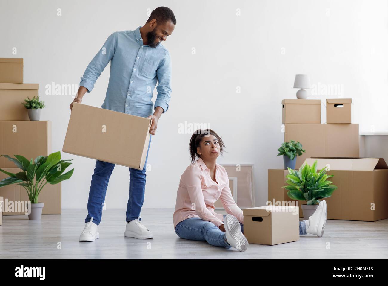 Cheerful young african american husband looks at tired sad wife ...